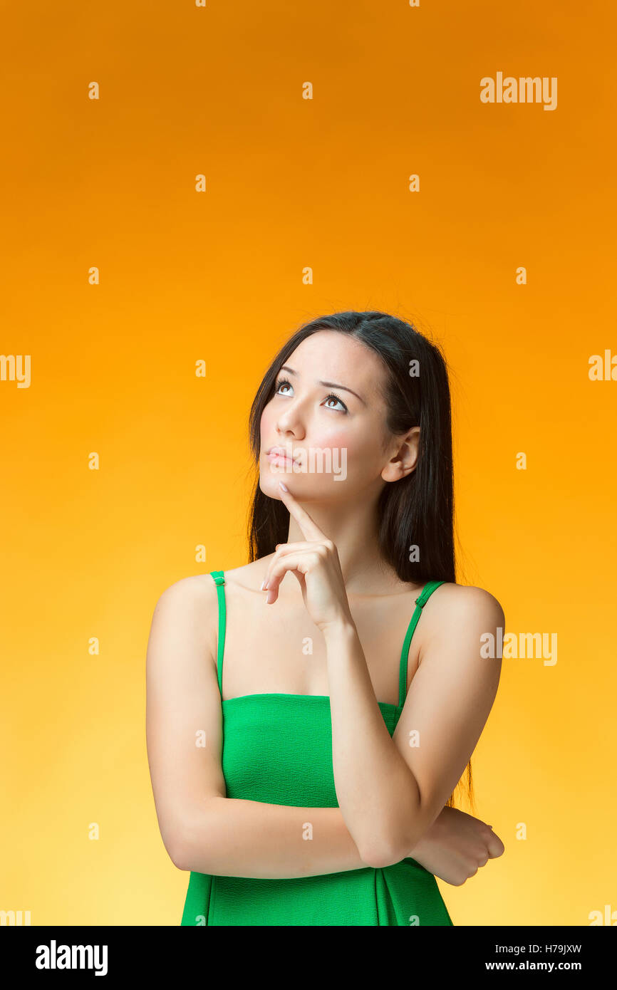 The thinking Chinese girl on yellow background Stock Photo - Alamy