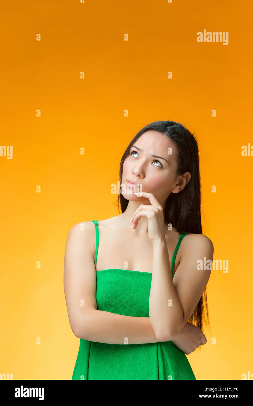 The thinking Chinese girl on yellow background Stock Photo - Alamy