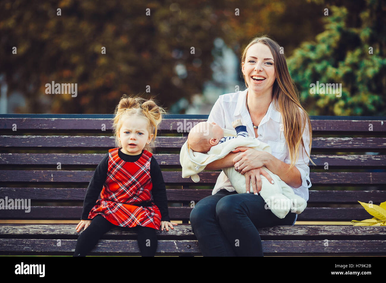 mother and two daughters rest on a bench Stock Photo - Alamy