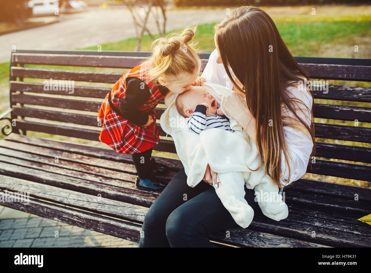 mother and two daughters rest on a bench Stock Photo - Alamy