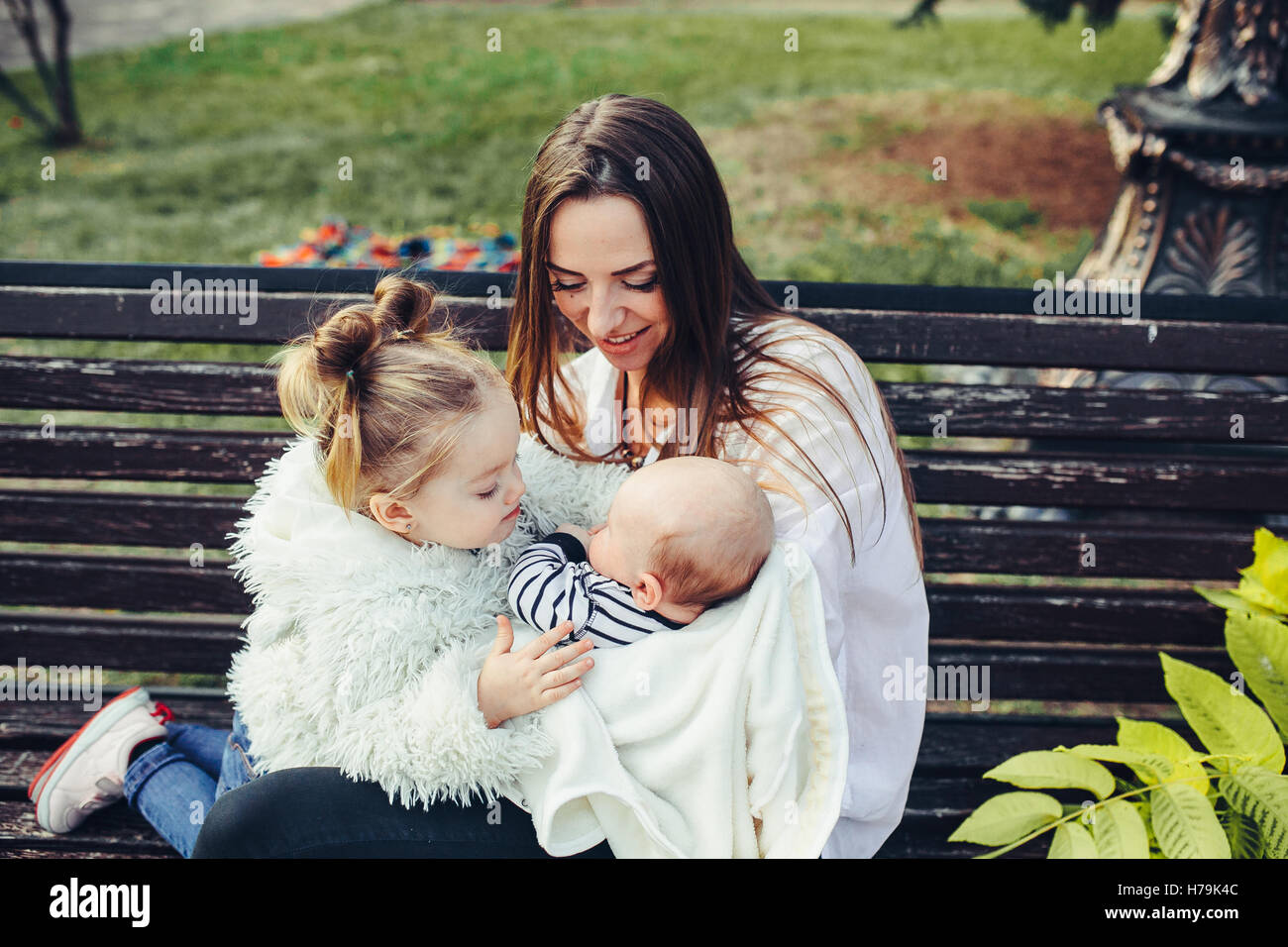 mother and two daughters rest on a bench Stock Photo - Alamy