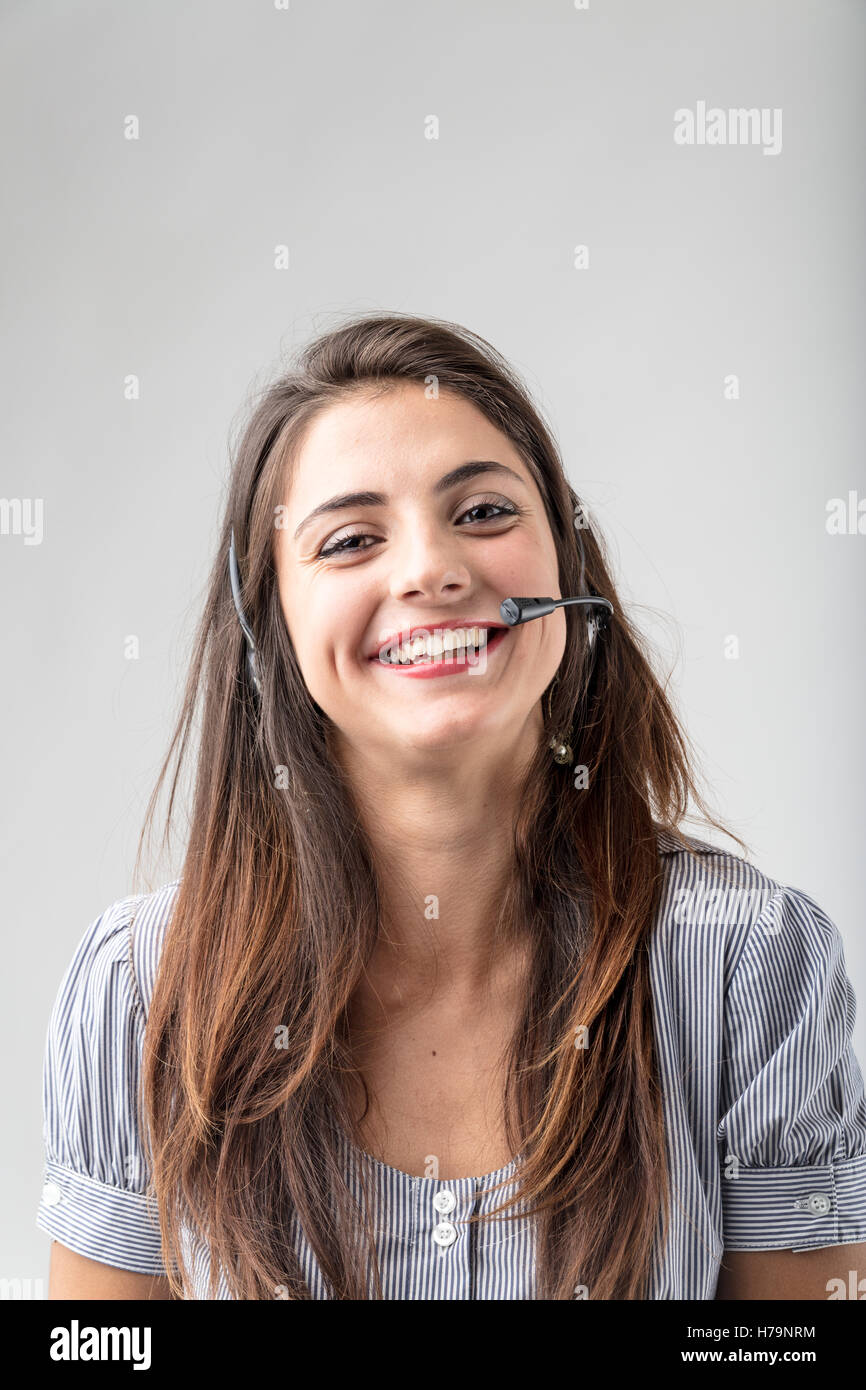 Happy vivacious young phone operator with long brown hair laughing as ...