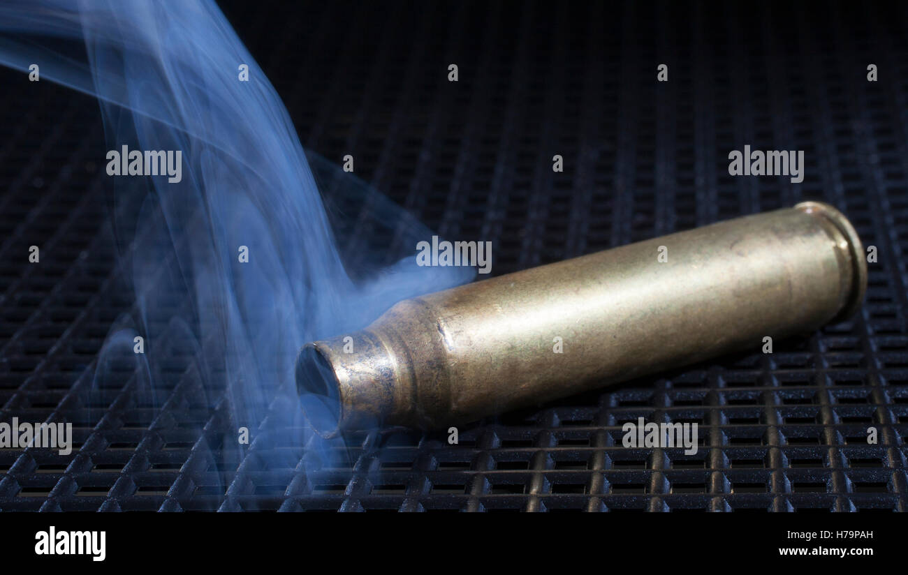 Empty rifle ammunition with smoke on a metal grate Stock Photo - Alamy