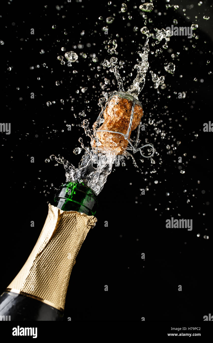 Champagne cork popping and splashing on black background. Party and ...