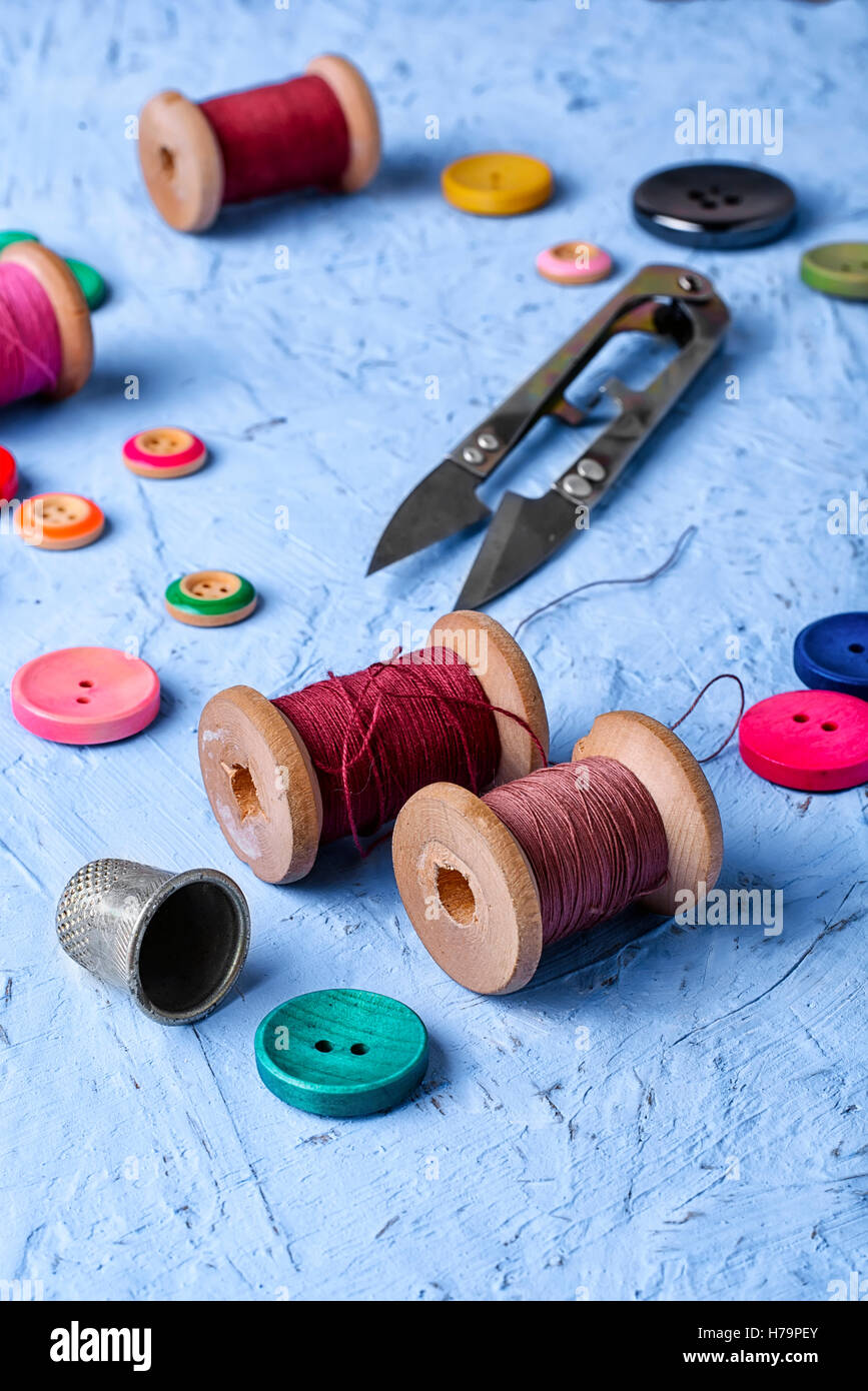 Set of buttons and thread on bright blue background Stock Photo - Alamy