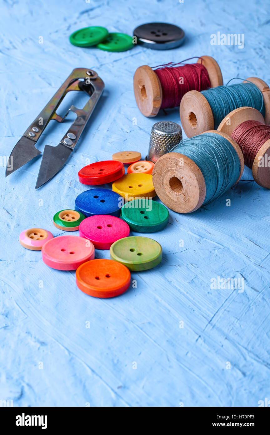 Set of buttons and thread on bright blue background Stock Photo - Alamy