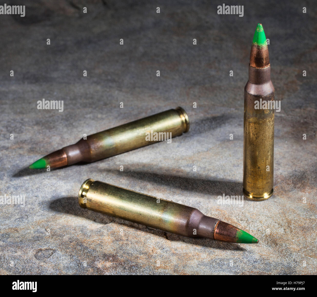 Green tipped rifle bullets that are on a stone background Stock Photo ...