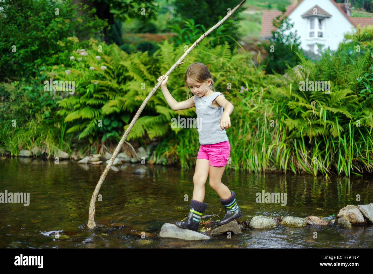 Cute little girl crossing river with cane, children outdoor games Stock ...