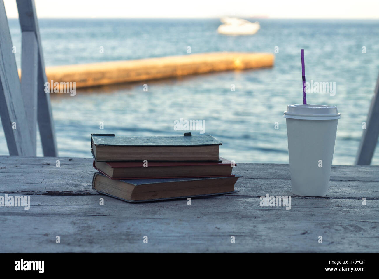 Old books on the beach with take away coffee. Sea water is on the ...