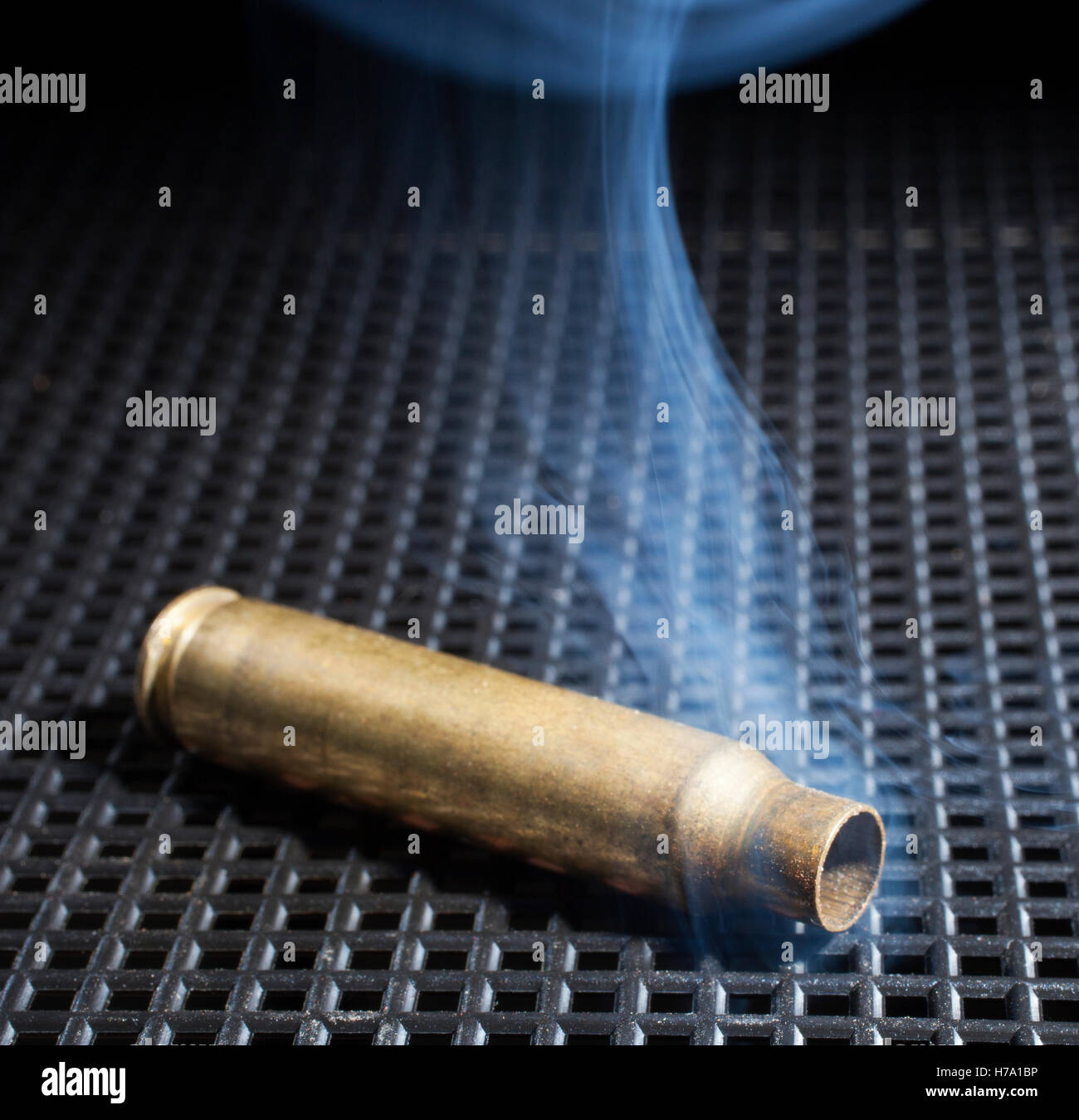 Empty rifle brass on a black grate with smoke around Stock Photo - Alamy