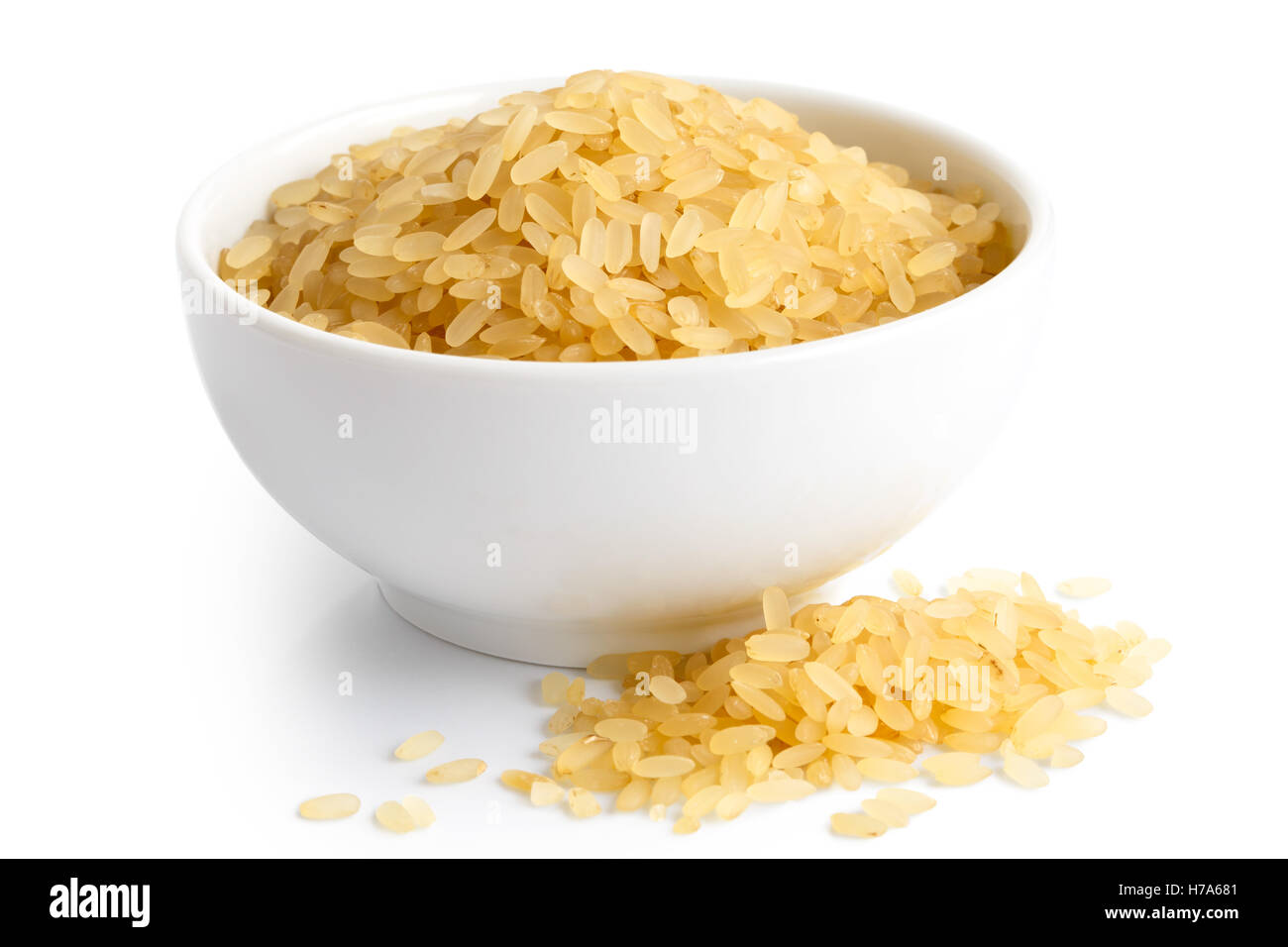 Bowl of short grain parboiled rice isolated on white. Spilled rice ...