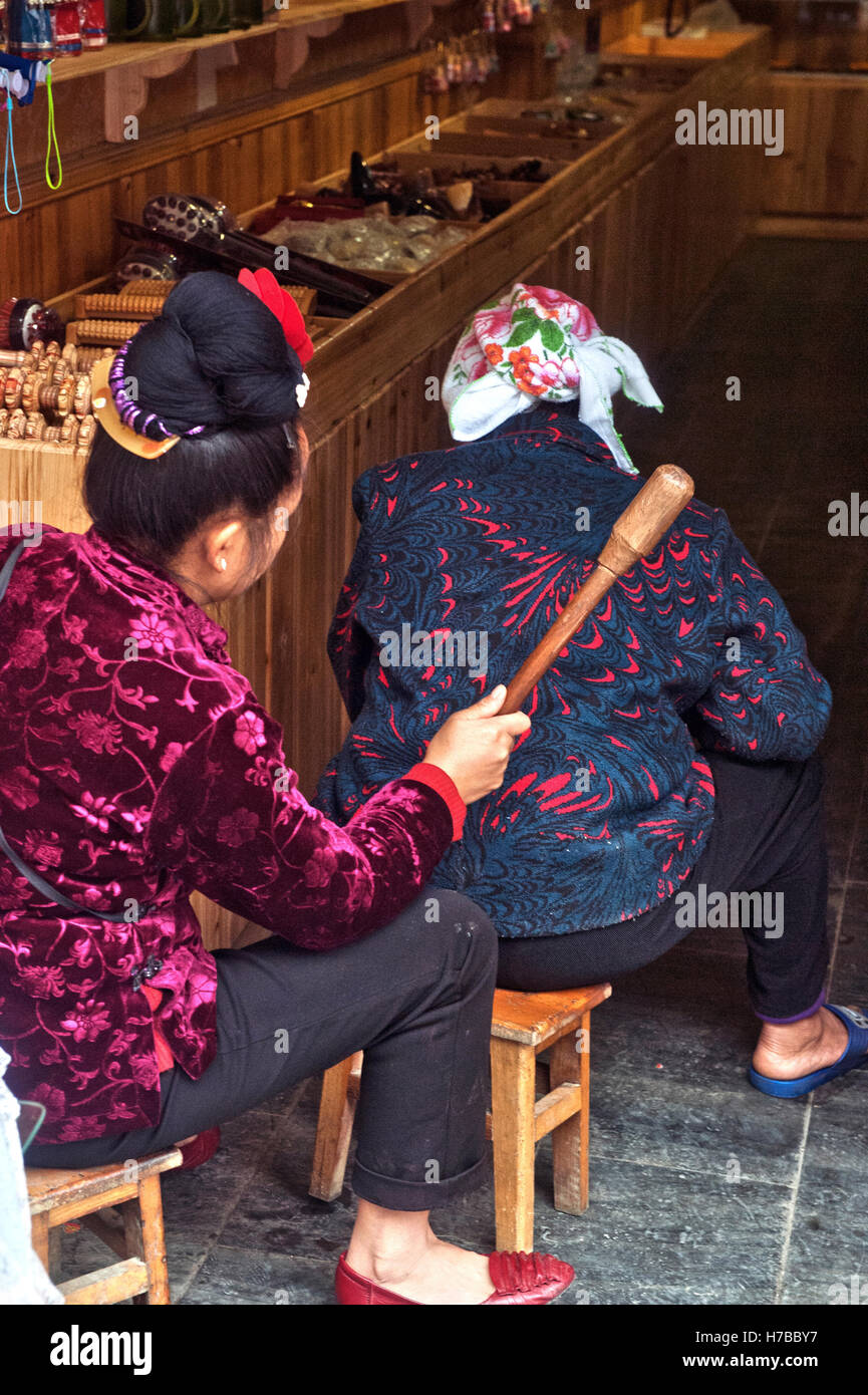 A Dong woman pats with a stick the back of her mother, in Zhaoxing ...