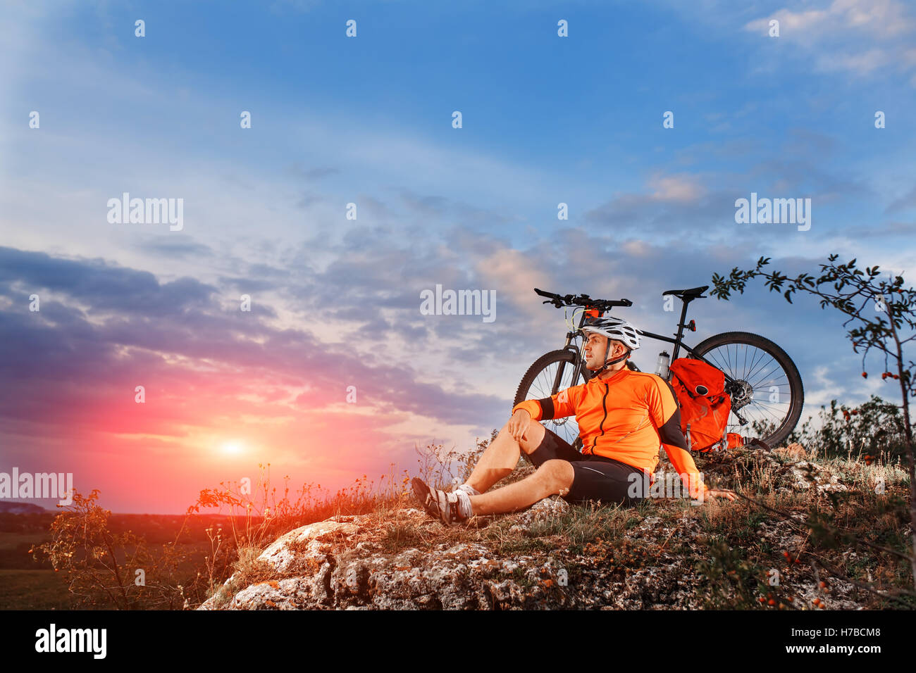 Biker resting on top of mountain with his bicycle near him. Cyclist ...