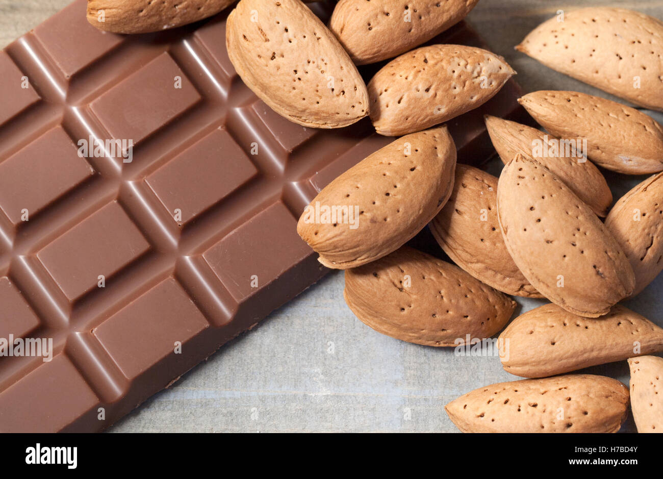 Close up of a bunch of raw almonds in their shells on a bar of milk ...