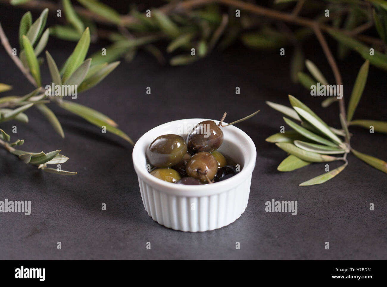 Black olives in dark background with olive tree leaves Stock Photo - Alamy