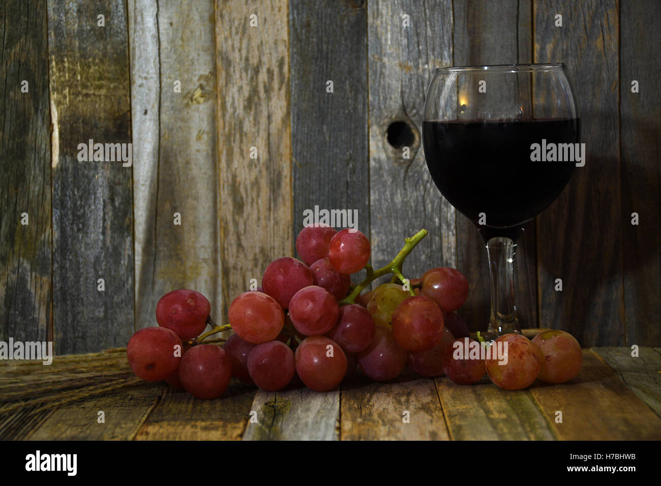 red wine in stemware with grapes on rustic barn wood Stock Photo - Alamy