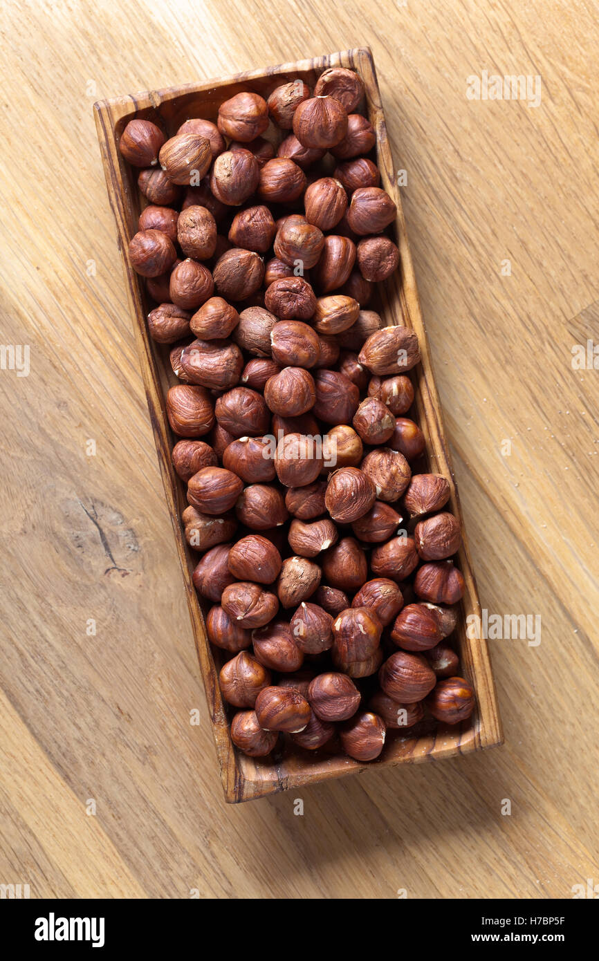 Hazelnuts in old wooden dish on a kitchen table Stock Photo - Alamy