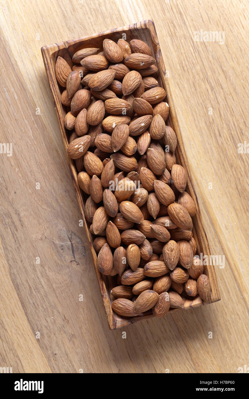 Almonds in old wooden dish on a kitchen table Stock Photo - Alamy