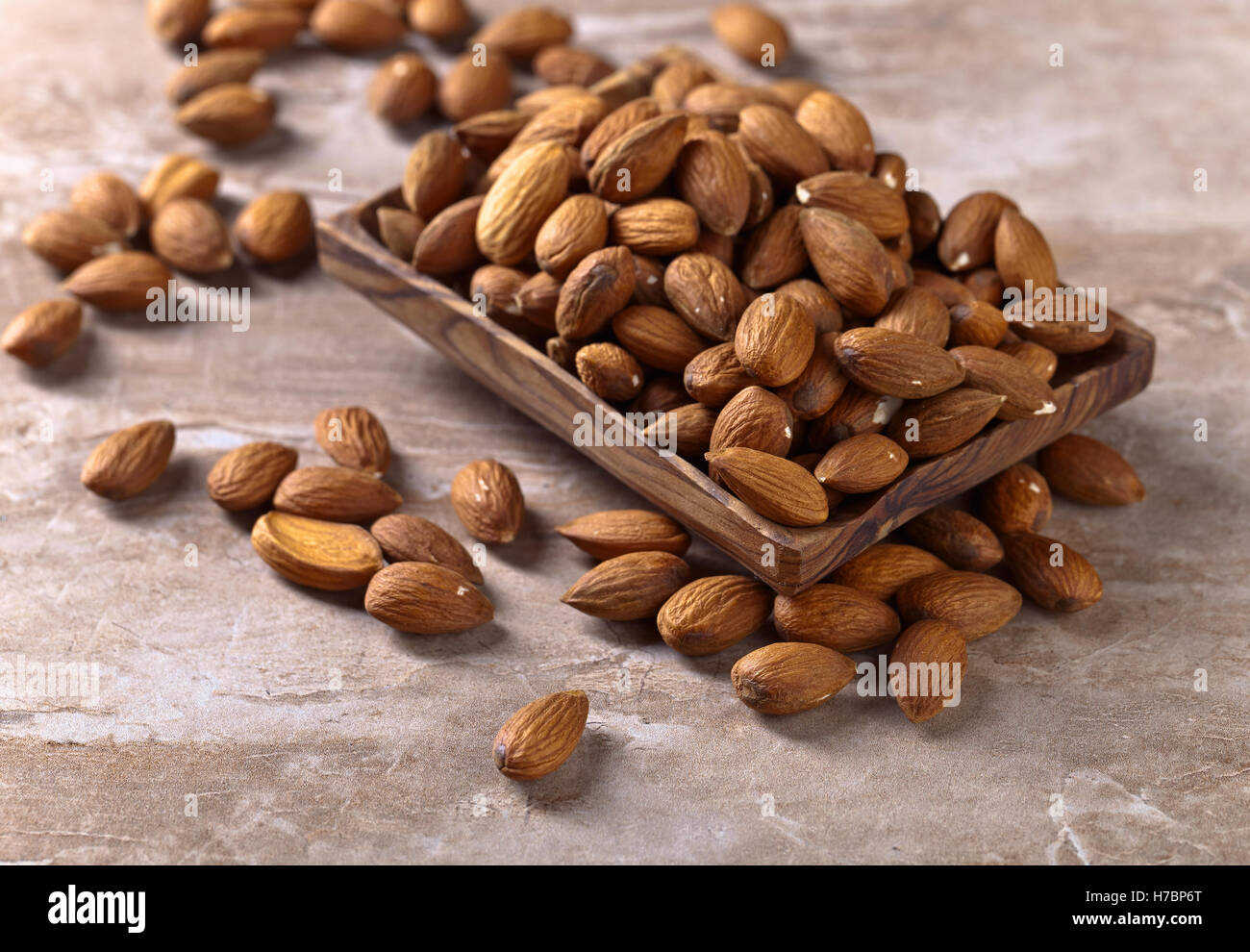 Almonds in old wooden dish on a kitchen table Stock Photo - Alamy