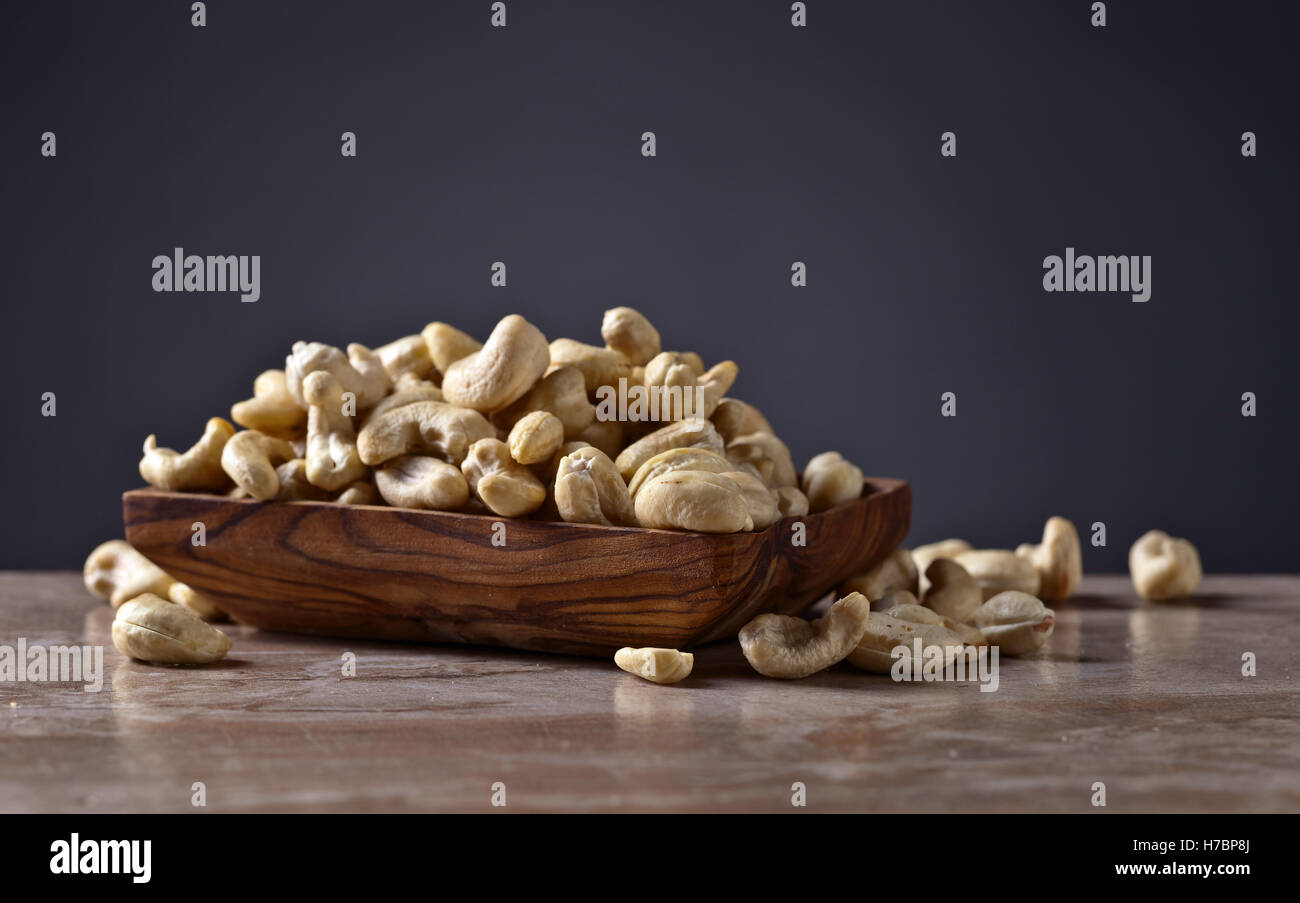 Cashews in old wooden dish on a kitchen table Stock Photo - Alamy