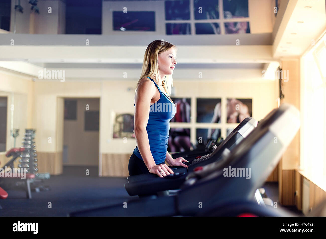 Horizontal shot of woman jogging on treadmill at health club. Female ...