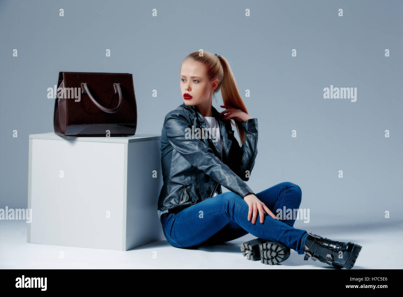 Fashion model with bag on white cube Stock Photo - Alamy