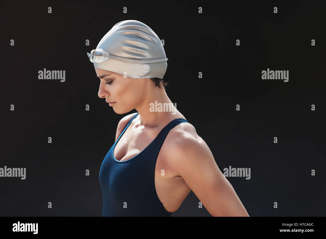 Side portrait of professional female swimmer standing on black ...