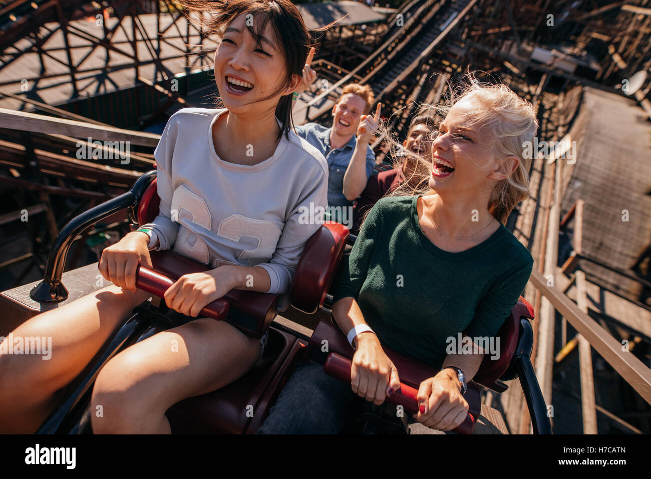 Shot of smiling young people riding a roller coaster. Young women and ...