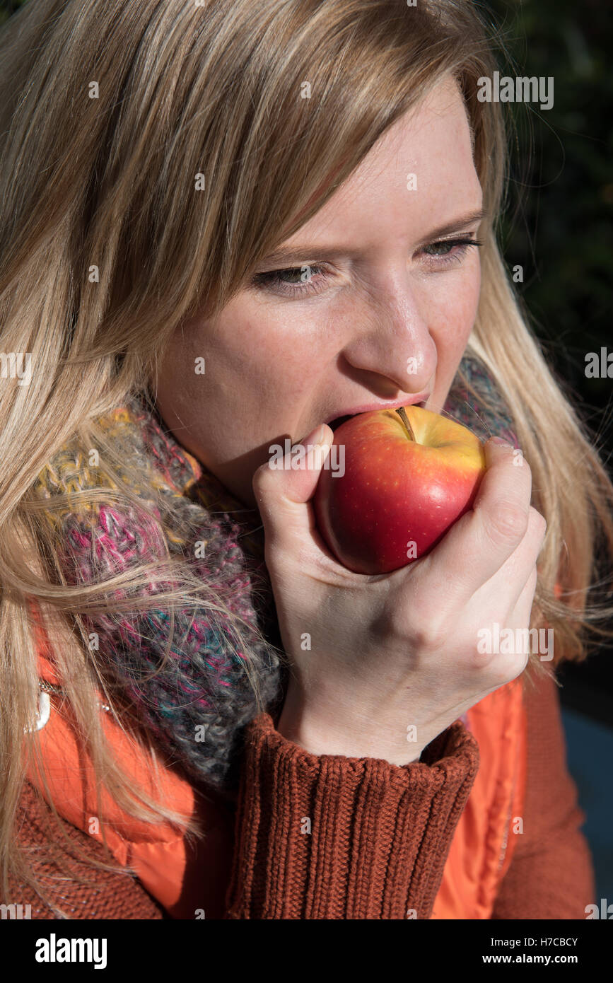 Attractive blond woman biting into an apple Stock Photo - Alamy