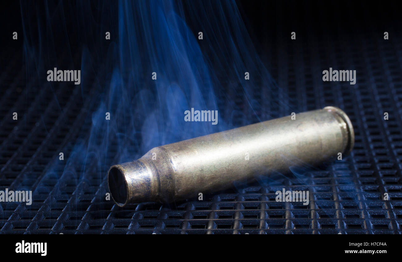 Smoke rising from a rifle casing on a black grate Stock Photo - Alamy