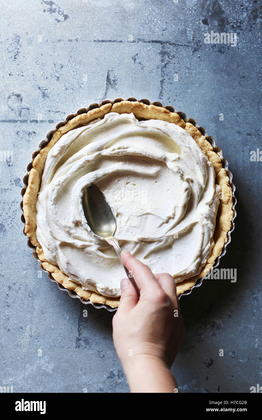 Hand spreading with the back of a spoon the whipped cream filling over ...