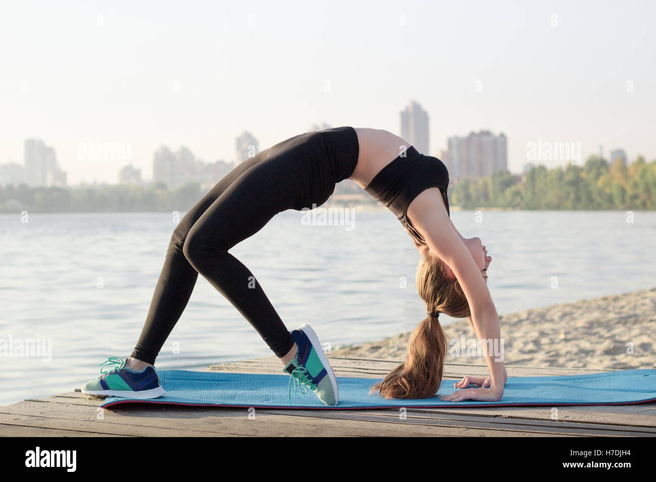 Young pretty slim fitness sporty woman stretches at arc bridge yoga ...