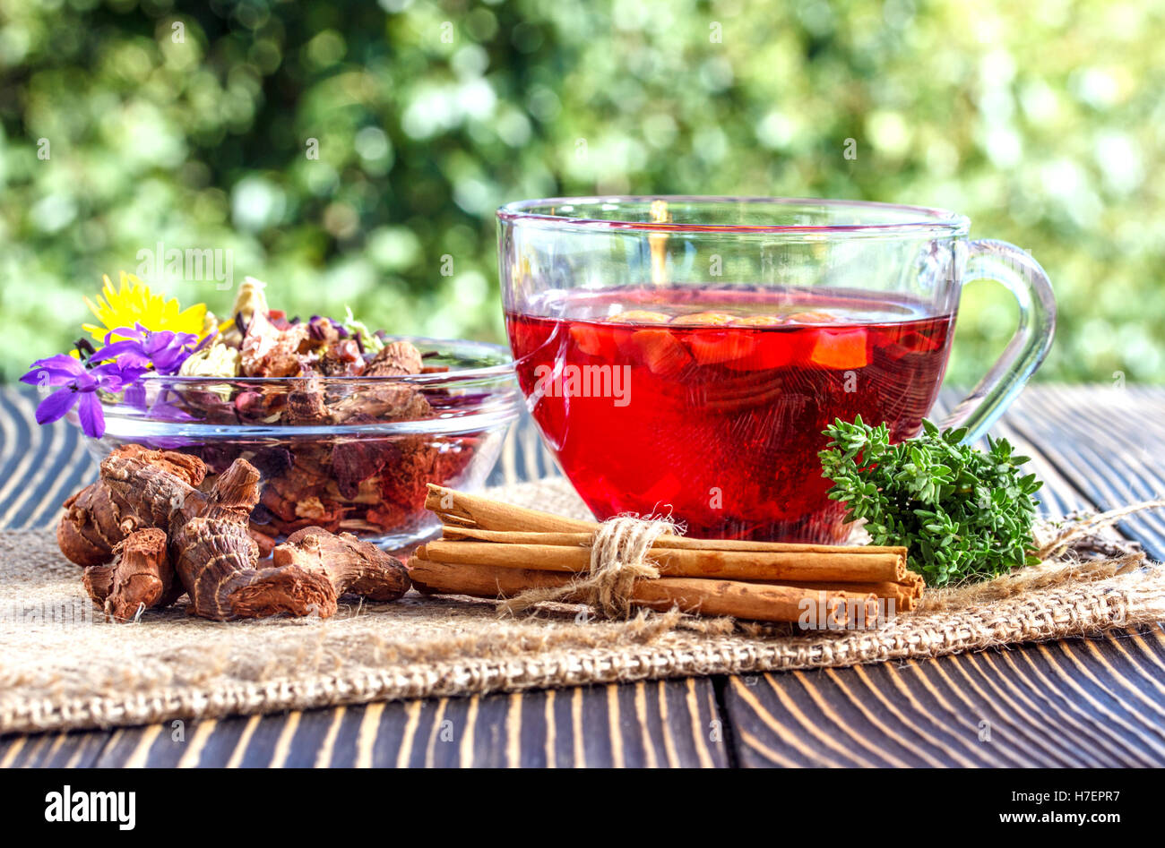 Cup of herbal tea with various herbs and dried fruit on a wooden table ...