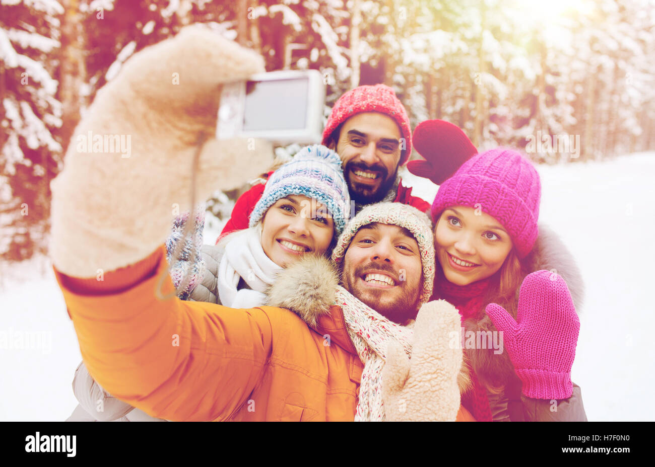 smiling friends with camera in winter forest Stock Photo - Alamy