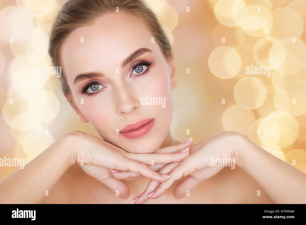 beautiful young woman face and hands over lights Stock Photo - Alamy