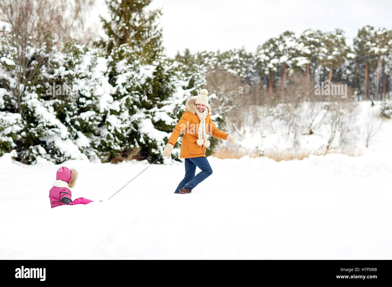 happy father pulling sled with child in winter Stock Photo - Alamy