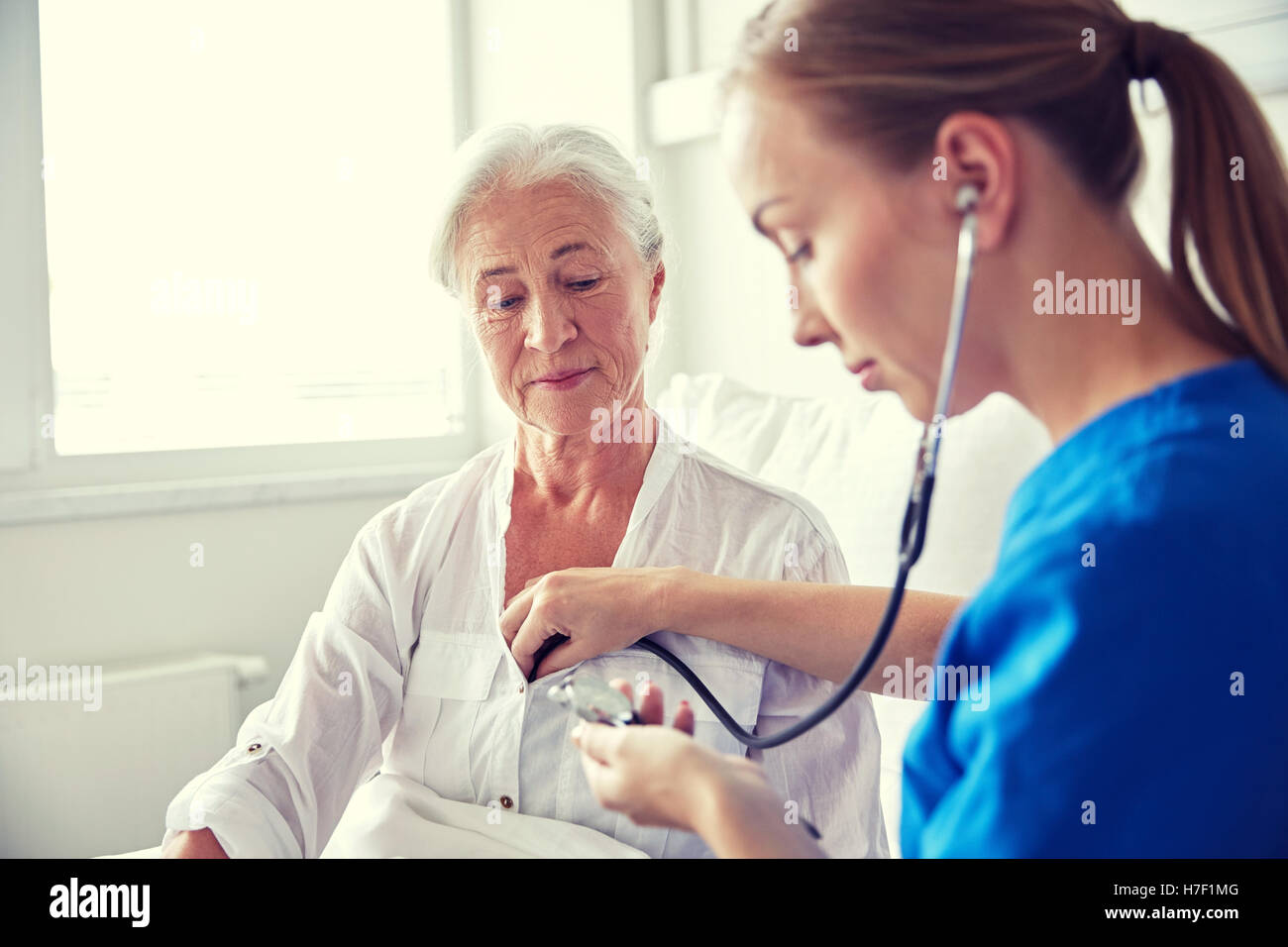 nurse with stethoscope and senior woman at clinic Stock Photo - Alamy
