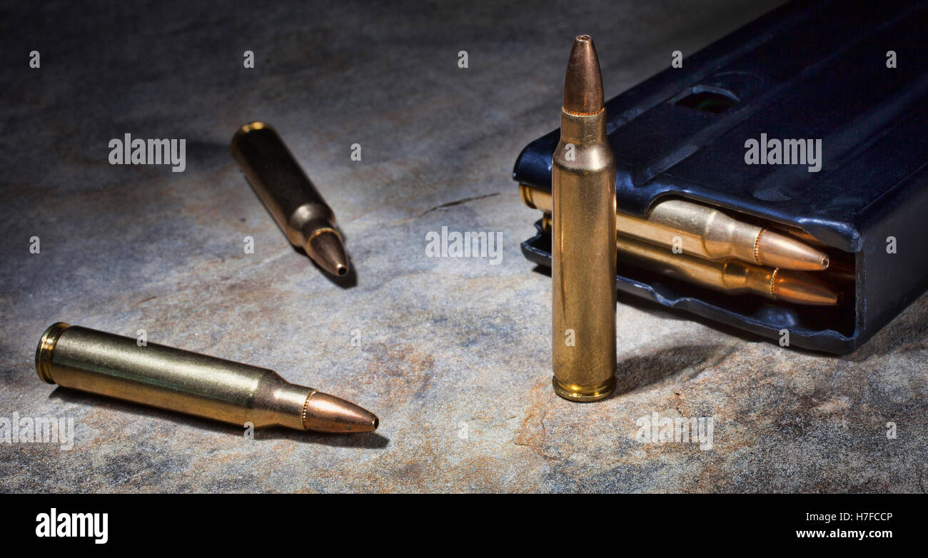 Rifle cartridges and a high capacity magazine on a rock background ...