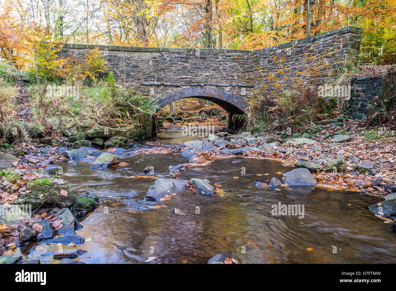 A stone footbridge which crosses over a small river in the countryside ...