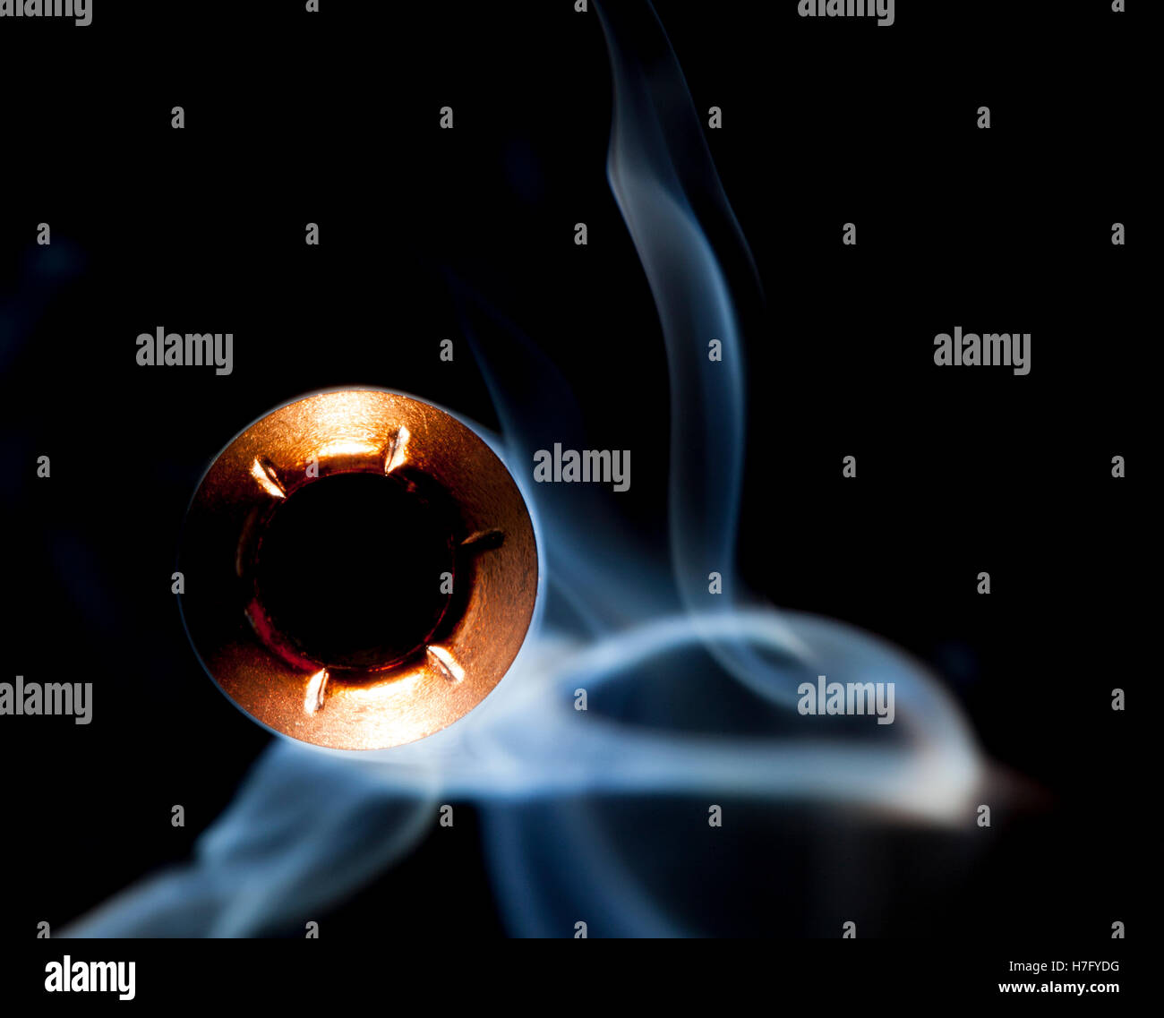 Copper colored hollow point bullet with smoke on a dark background ...