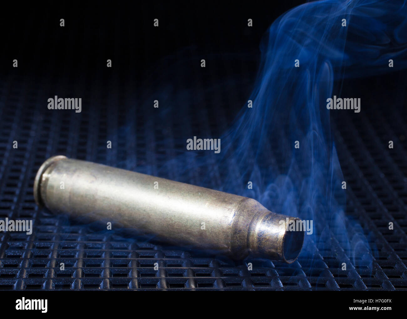 Empty rifle brass on a black grate that is smoking Stock Photo - Alamy