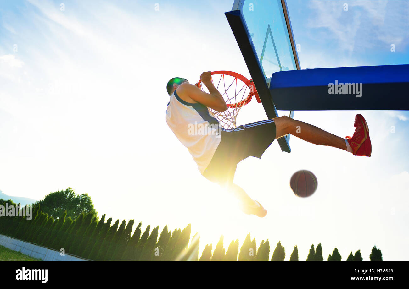Street basketball player performing power slum dunk Stock Photo - Alamy