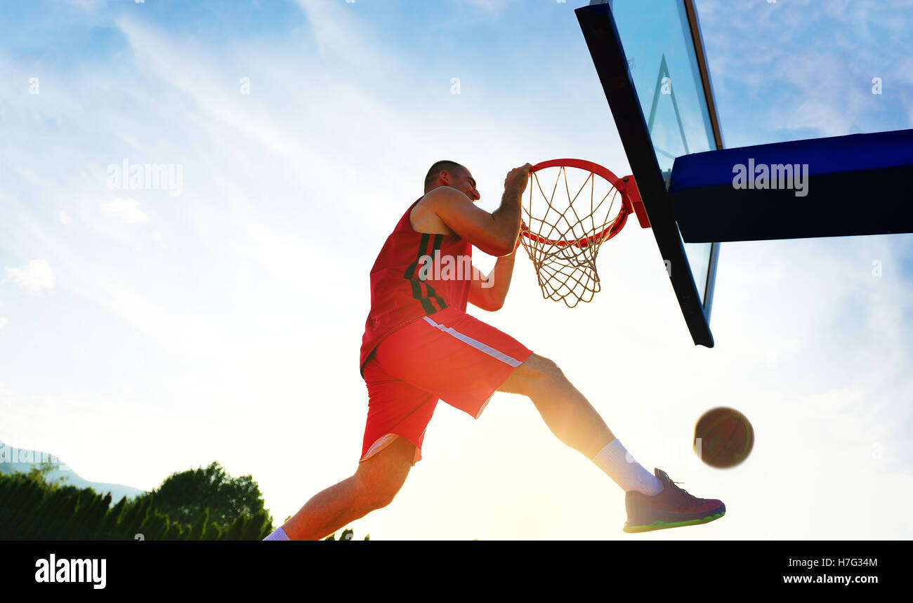 Young basketball player drives to the hoop for a high flying slam dunk ...