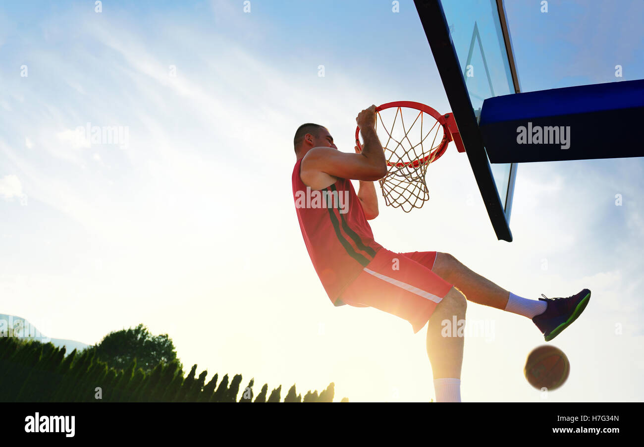 Young basketball player drives to the hoop for a high flying slam dunk ...