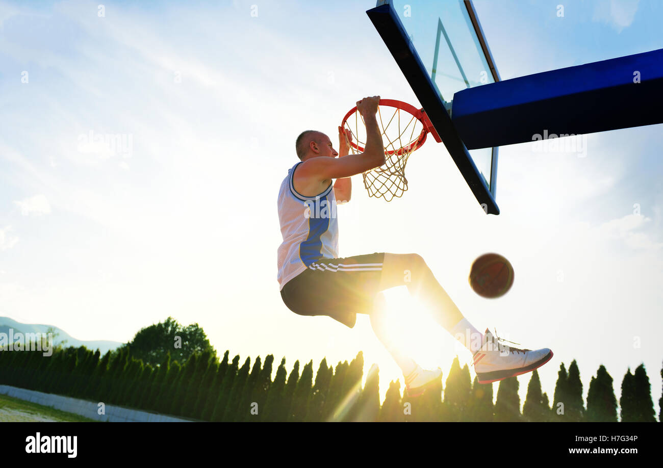 Young basketball player drives to the hoop for a high flying slam dunk ...