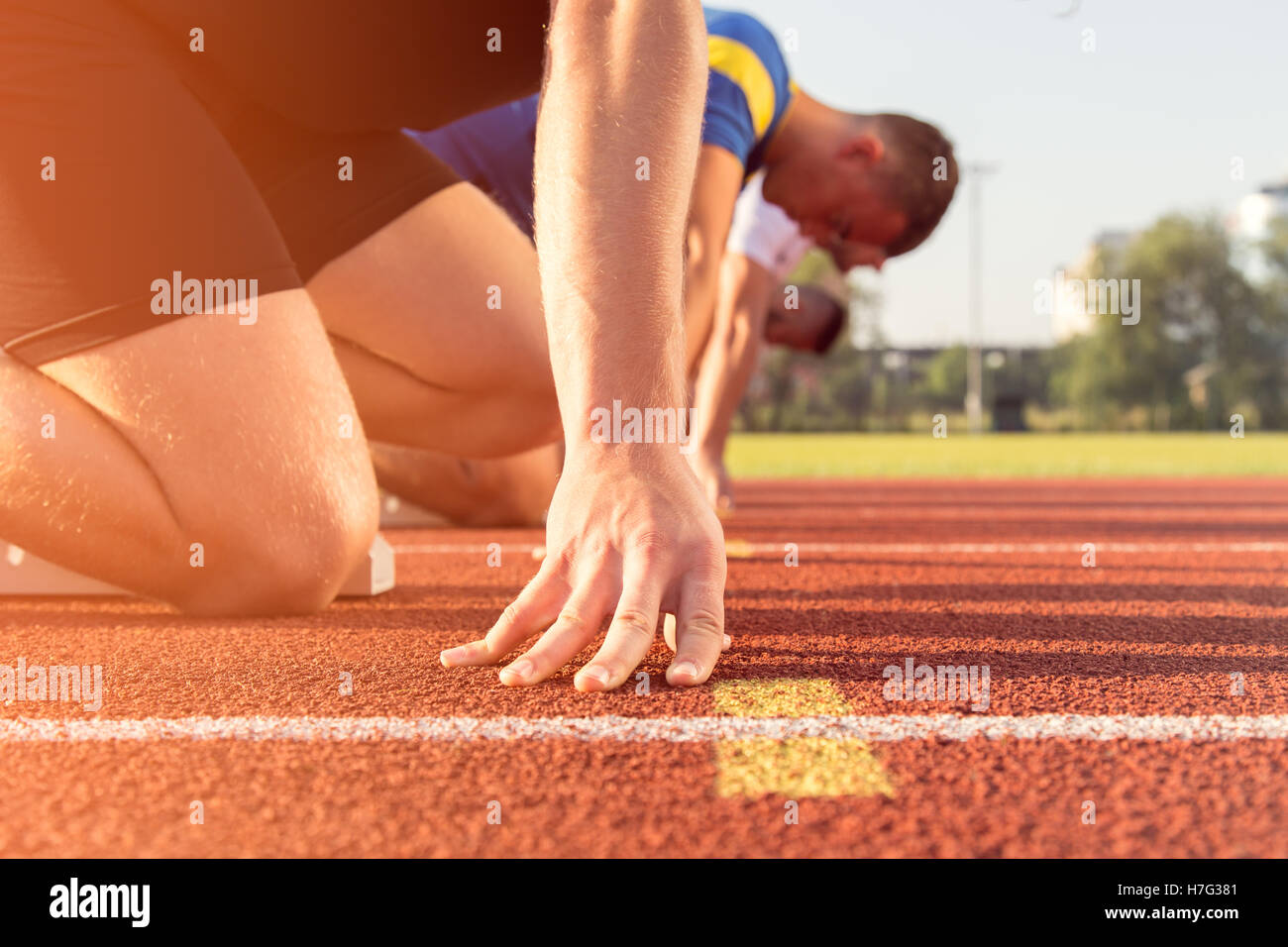 Male athletes at starting line on sunny day Stock Photo - Alamy