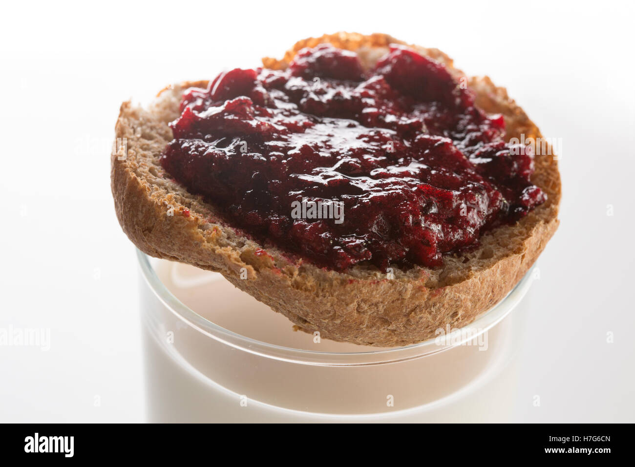Toasted bread with layer of black currant jam on top of colorless glass ...