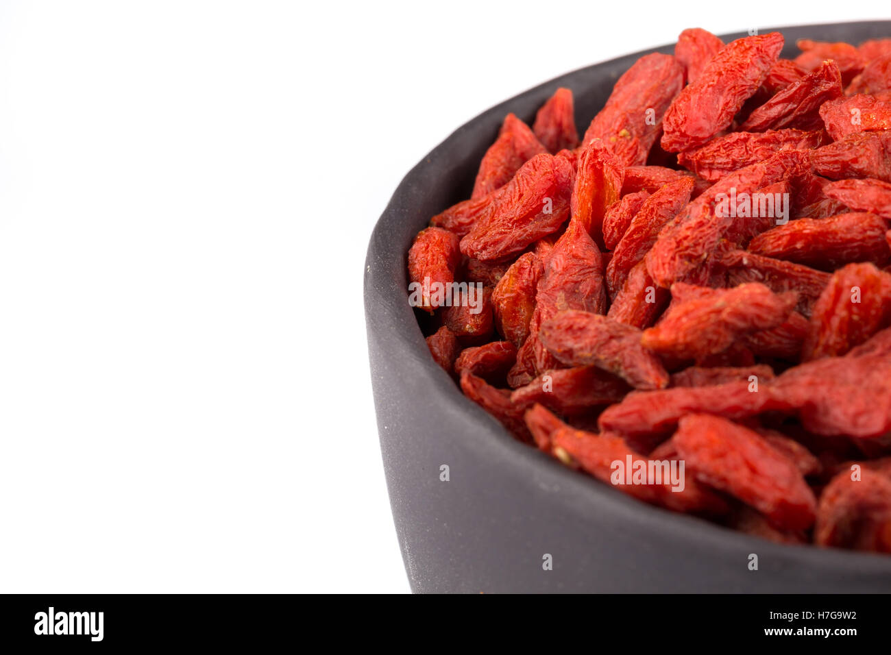 Chinese goji berries in dark stone bowl close up on white background ...