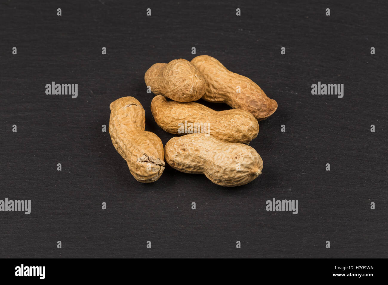 Raw peanuts shells over dark stone background Stock Photo - Alamy