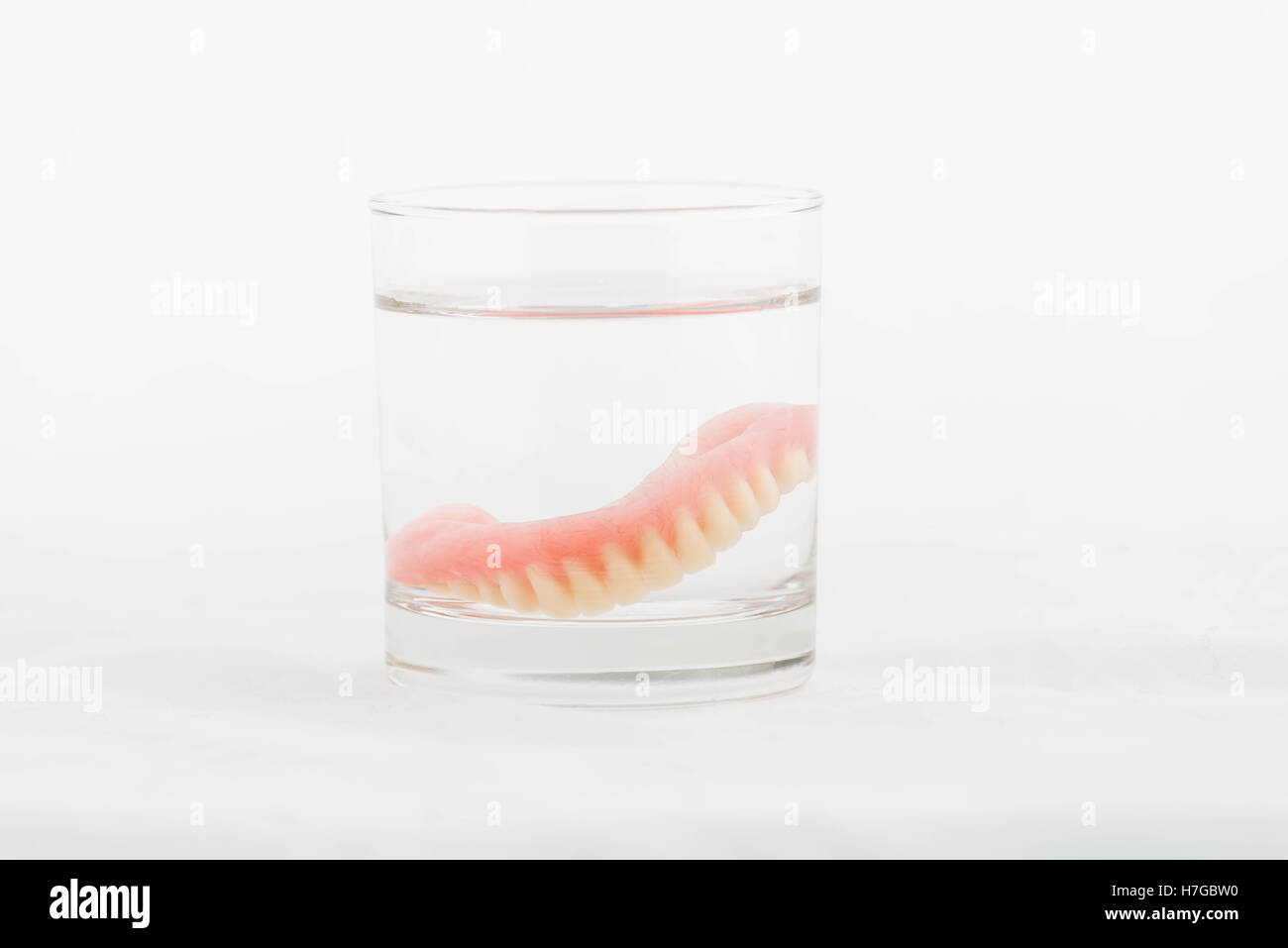 dentures in glass of water on white background Stock Photo - Alamy
